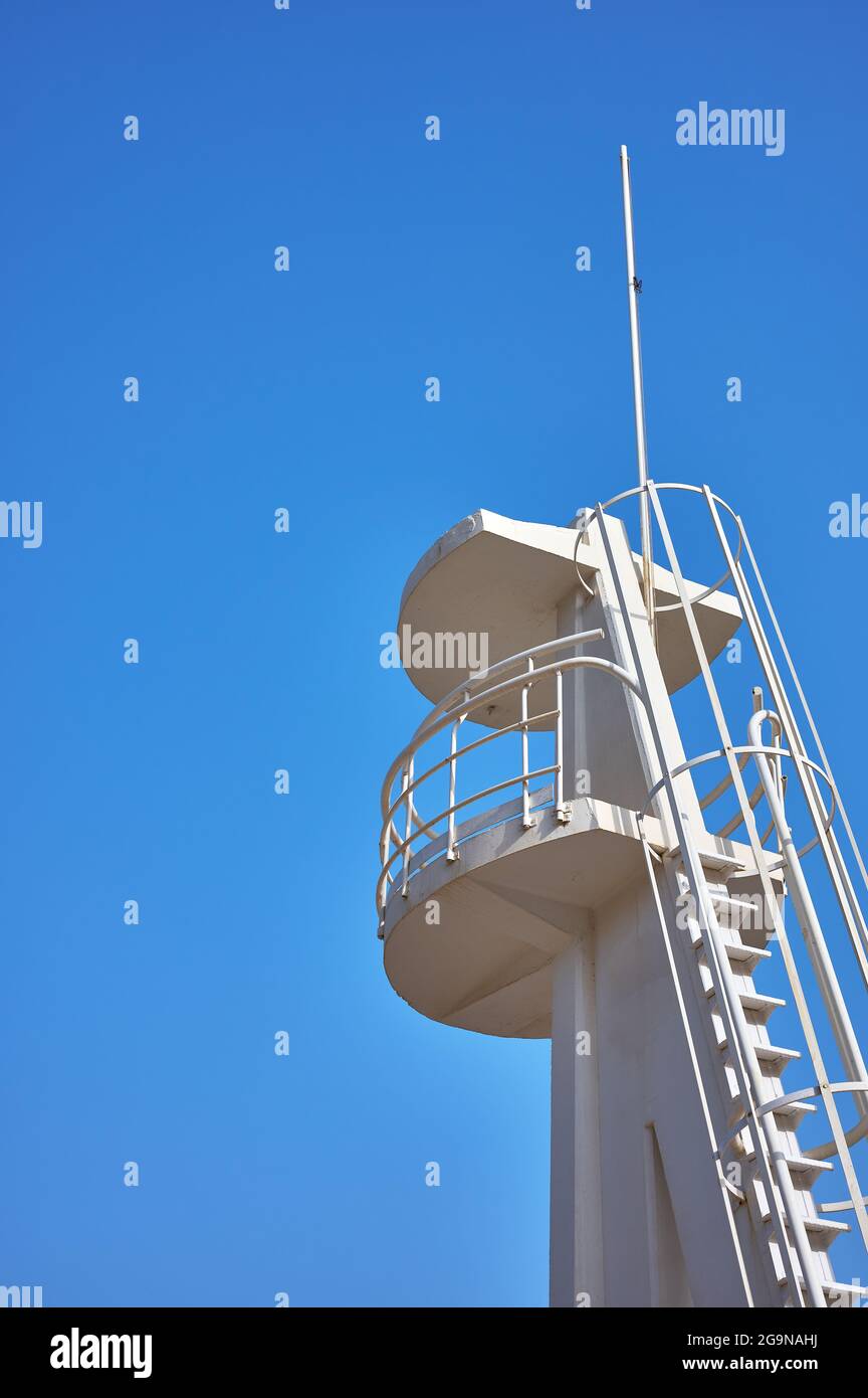 detail of a white concrete watchtower with metal railings on a blue ...