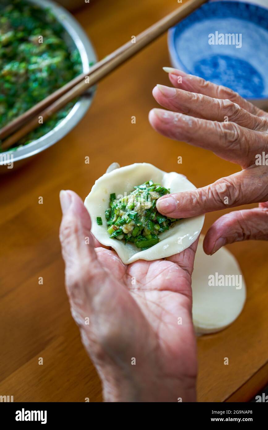 An old man in a Chinese family makes dumplings by hand Stock Photo - Alamy