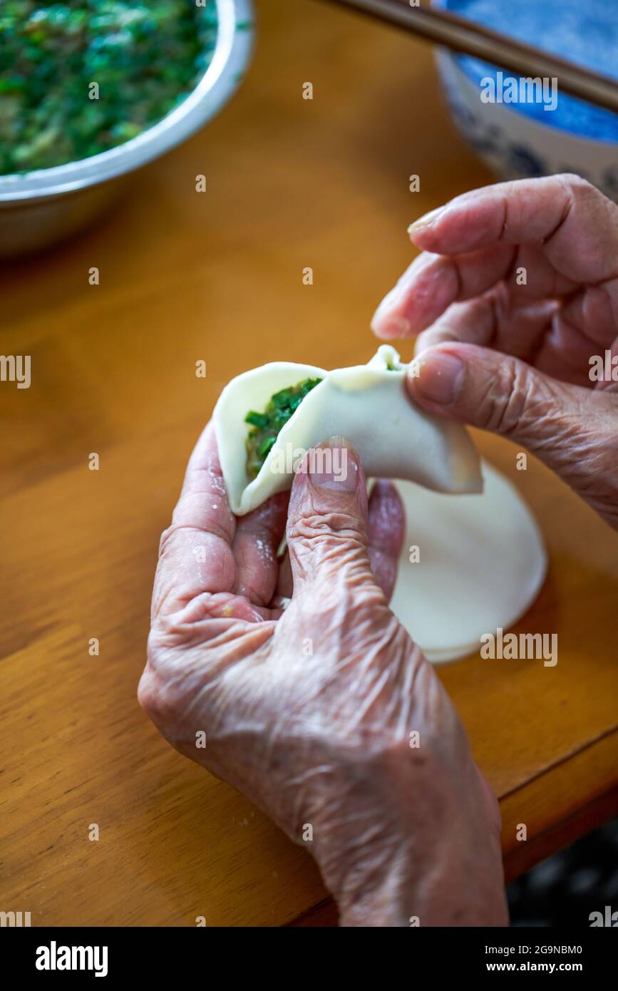 An old man in a Chinese family makes dumplings by hand Stock Photo - Alamy