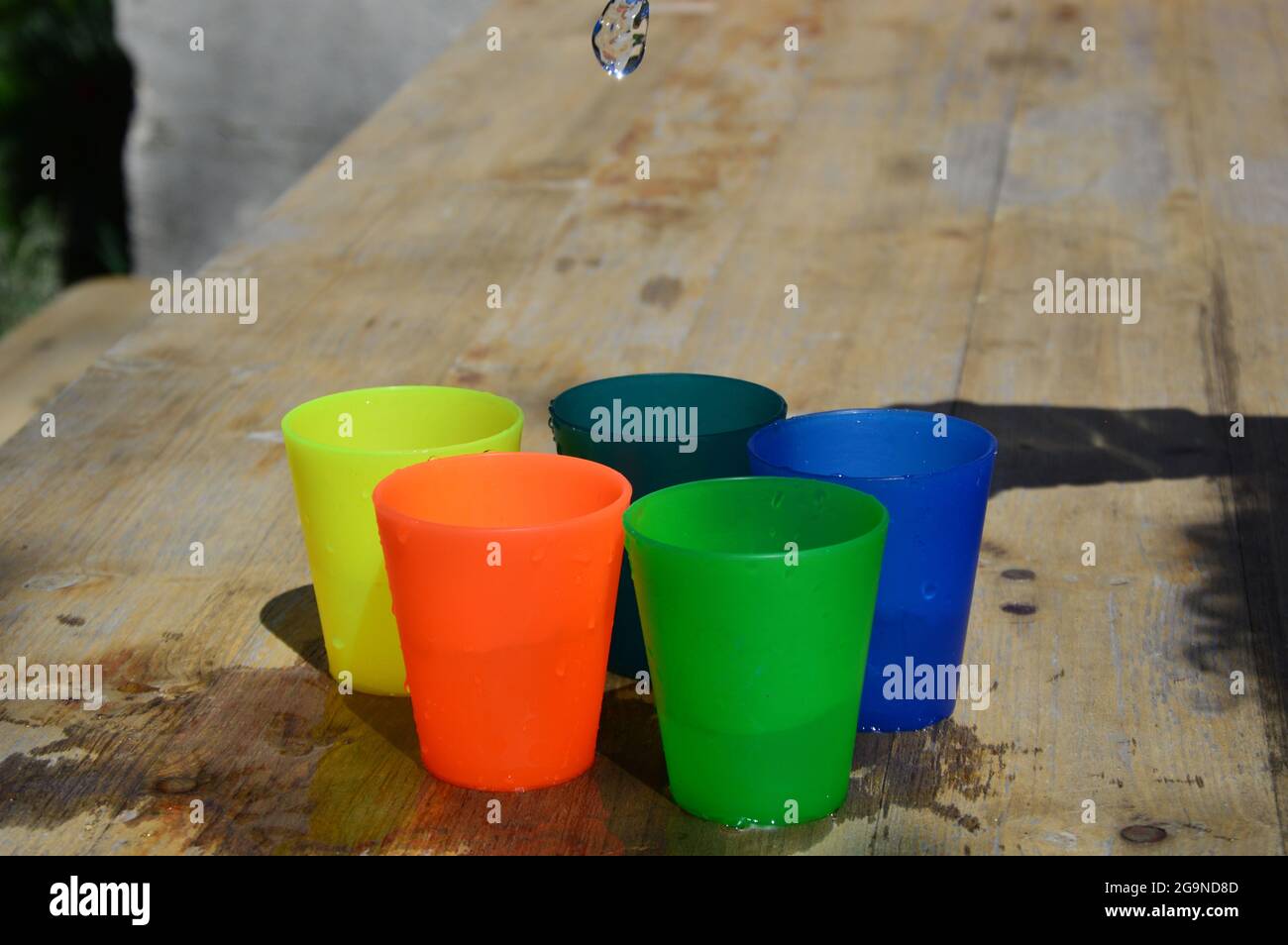 Water pouring into colorful plastic cups Stock Photo - Alamy