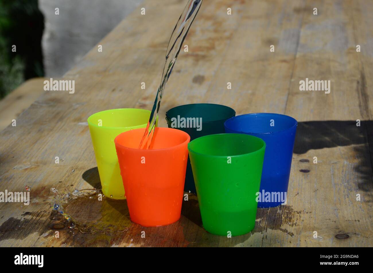 Water pouring into colorful plastic cups Stock Photo - Alamy