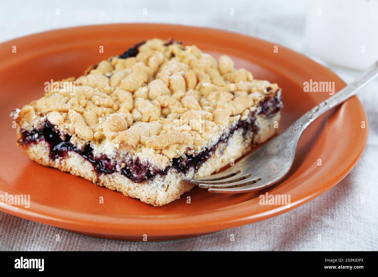 Homemade grated pie with jam and glass of milk on tablecloth background ...