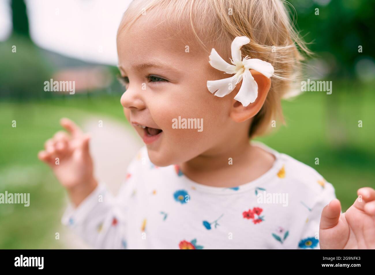 Little funny girl with a flower behind her ear. Portrait Stock Photo ...