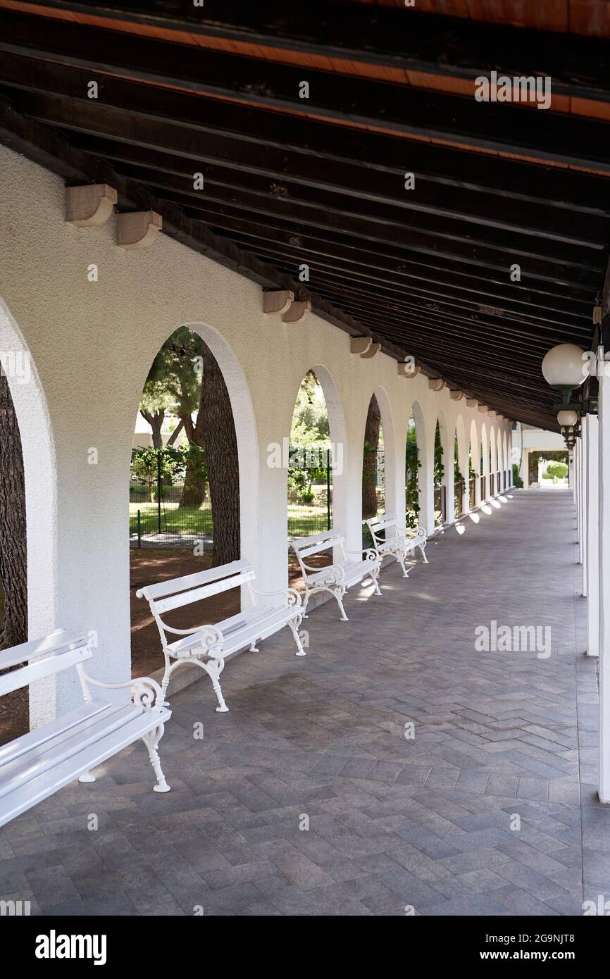 Long pavilion with arches and benches in a green park Stock Photo - Alamy