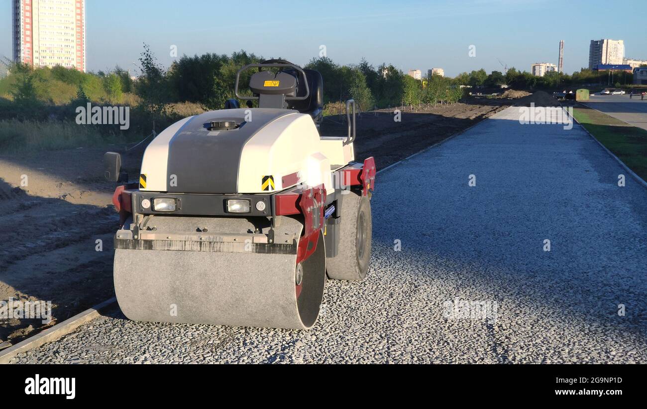 Road roller tamping asphalt or paver machine levels rubble before ...