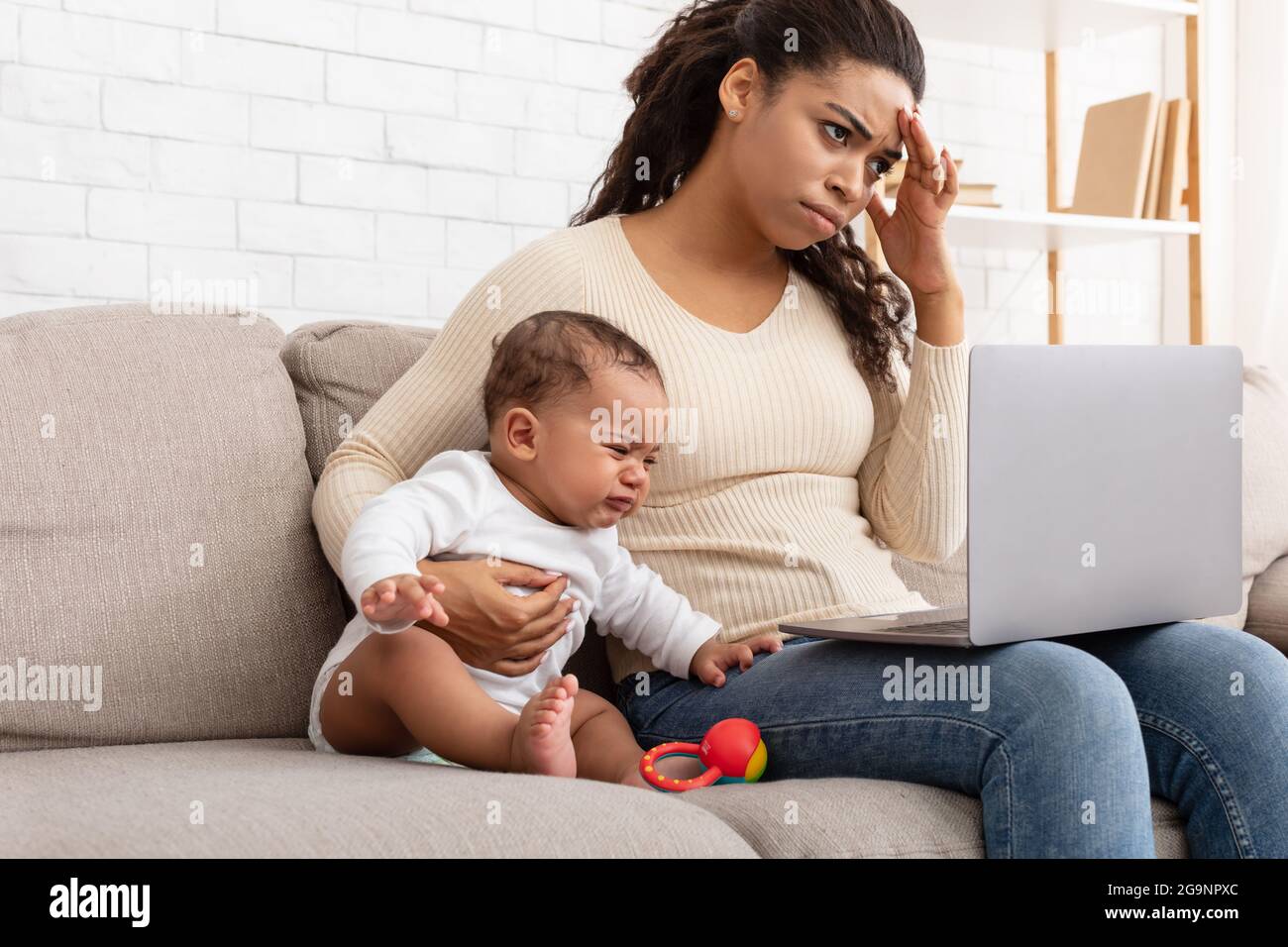 African Mother Trying Work On Computer While Infant Screaming Indoor ...