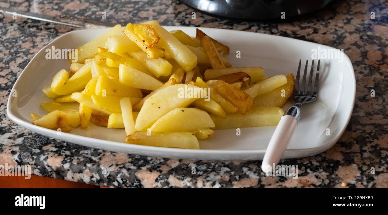 French fries already cooked served on dish with a fork Stock Photo - Alamy