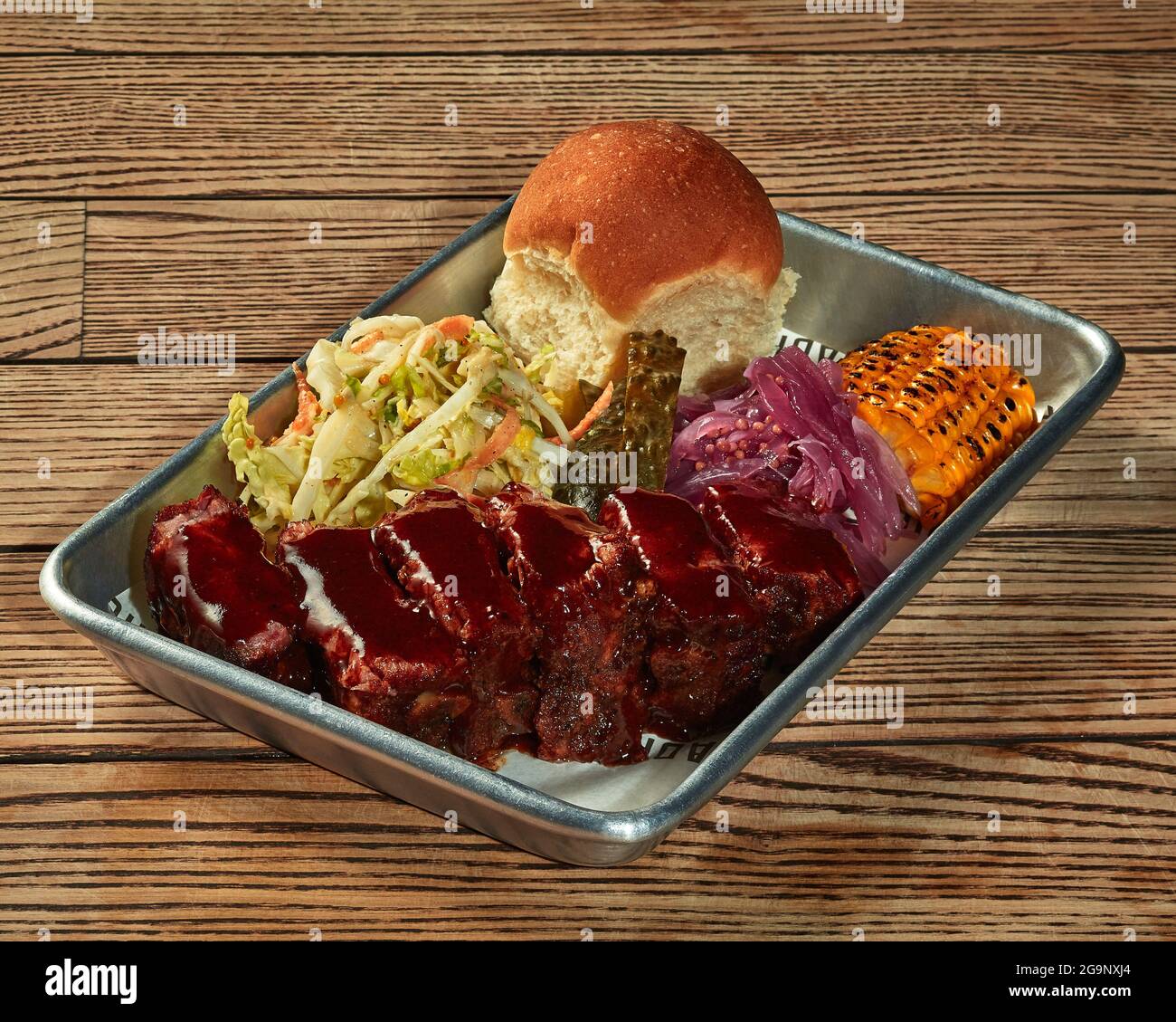 Baked pork loin with barbecue sauce and vegetable garnish on plastic ...