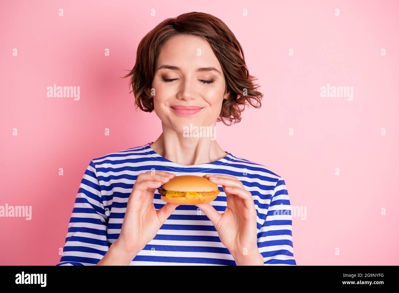 Portrait of young beautiful smiling hungry girl with closed hold ...