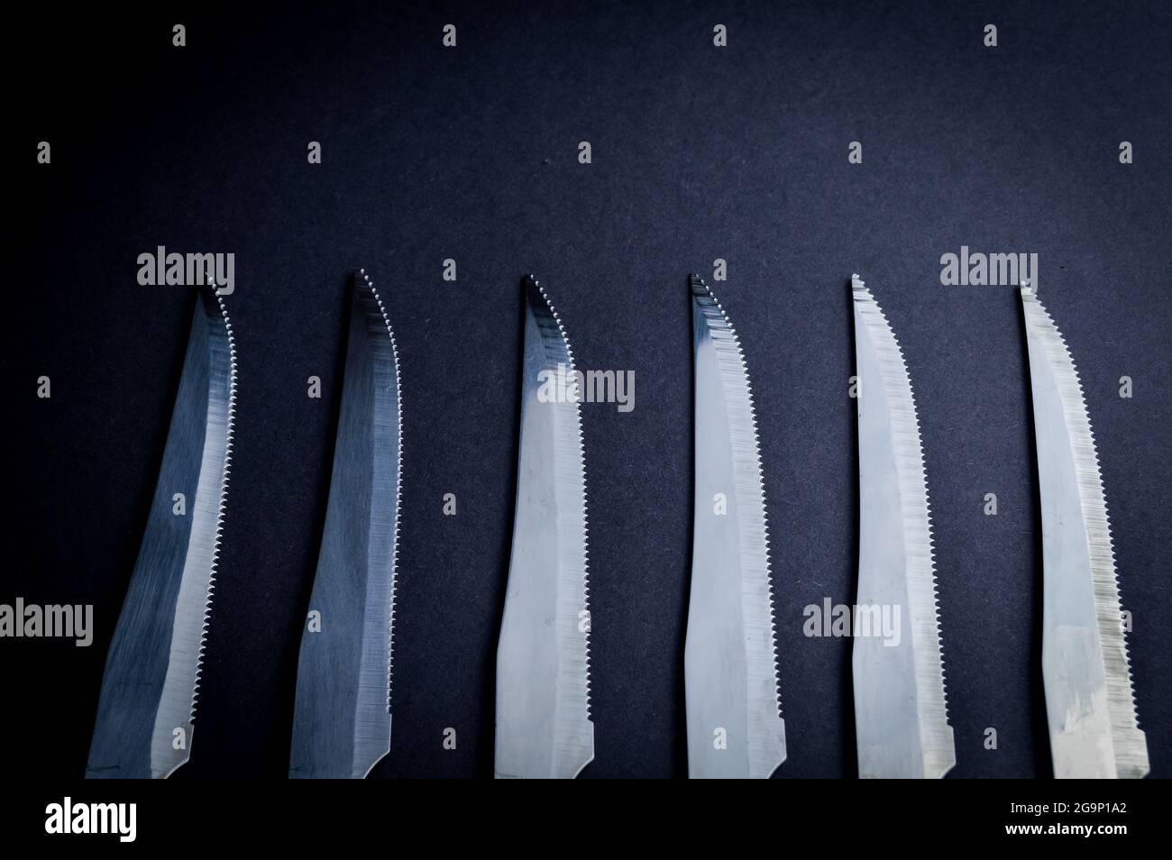 kitchen knife blades on dark gray background, blue toned image ...