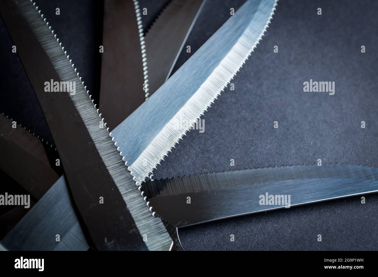 kitchen knife blades on dark gray background, blue toned image ...