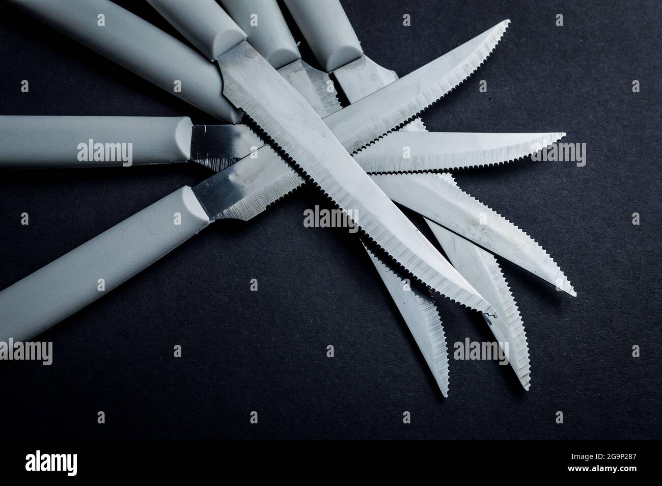 kitchen knife blades on dark gray background, blue toned image ...