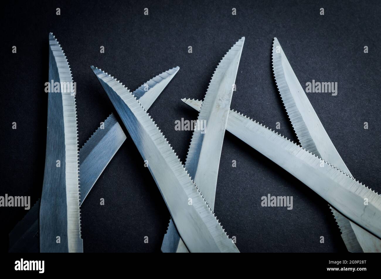 kitchen knife blades on dark gray background, blue toned image ...