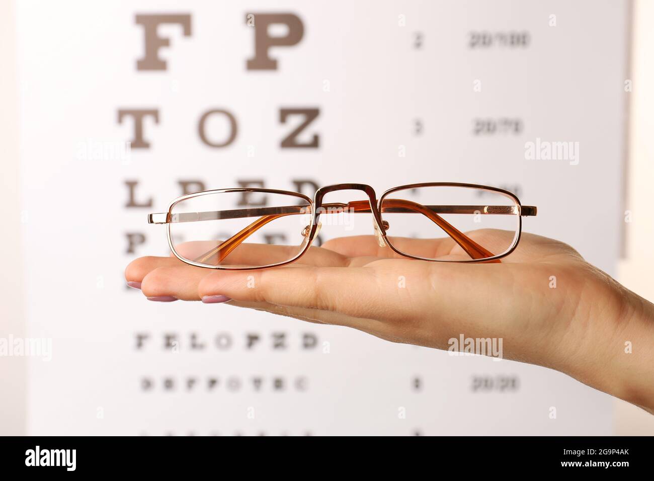 Eye glasses in female hand on eyesight test chart background Stock ...