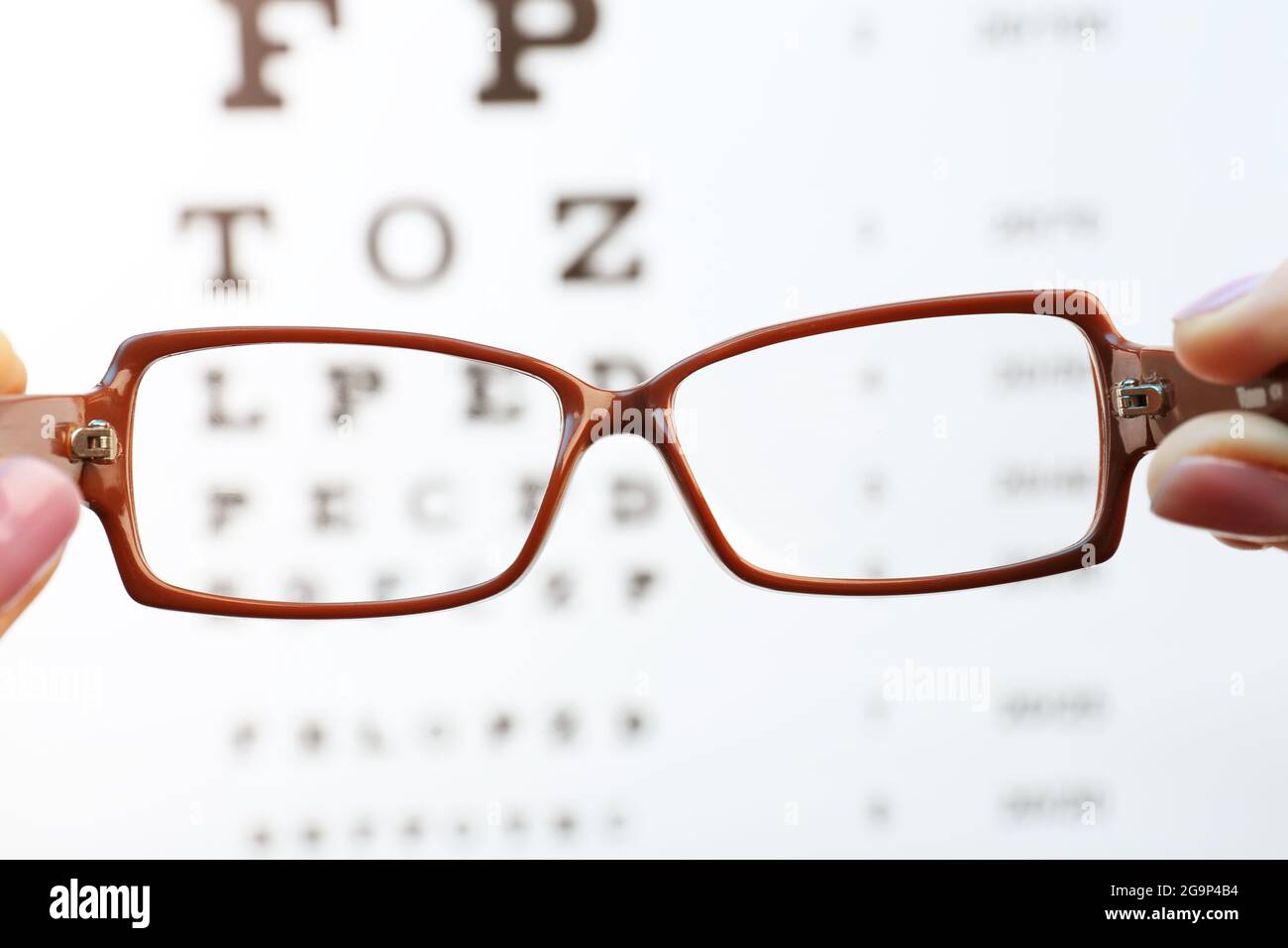Eye glasses in female hands on eyesight test chart background Stock ...