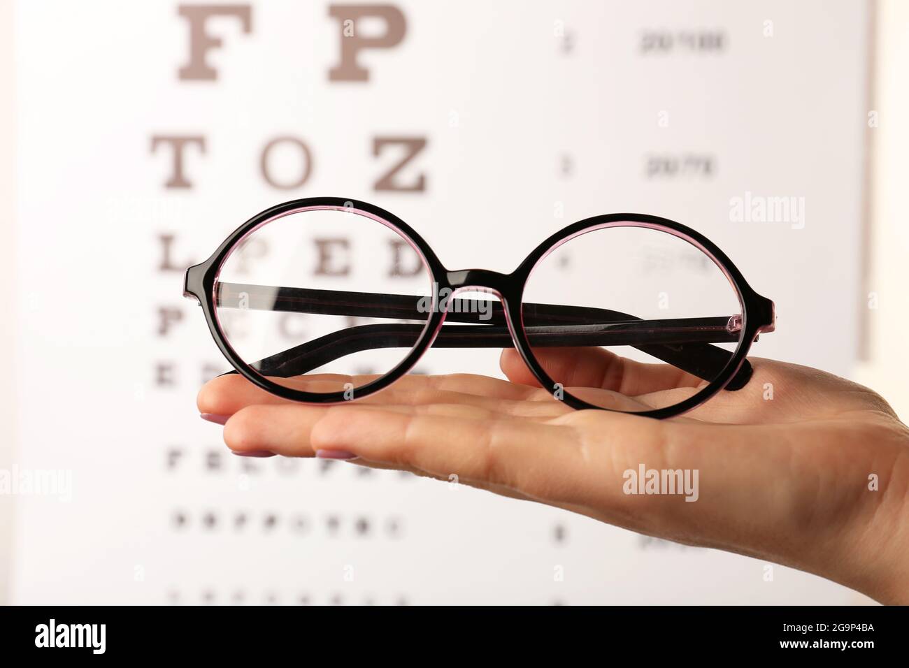 Eye glasses in female hand on eyesight test chart background Stock ...
