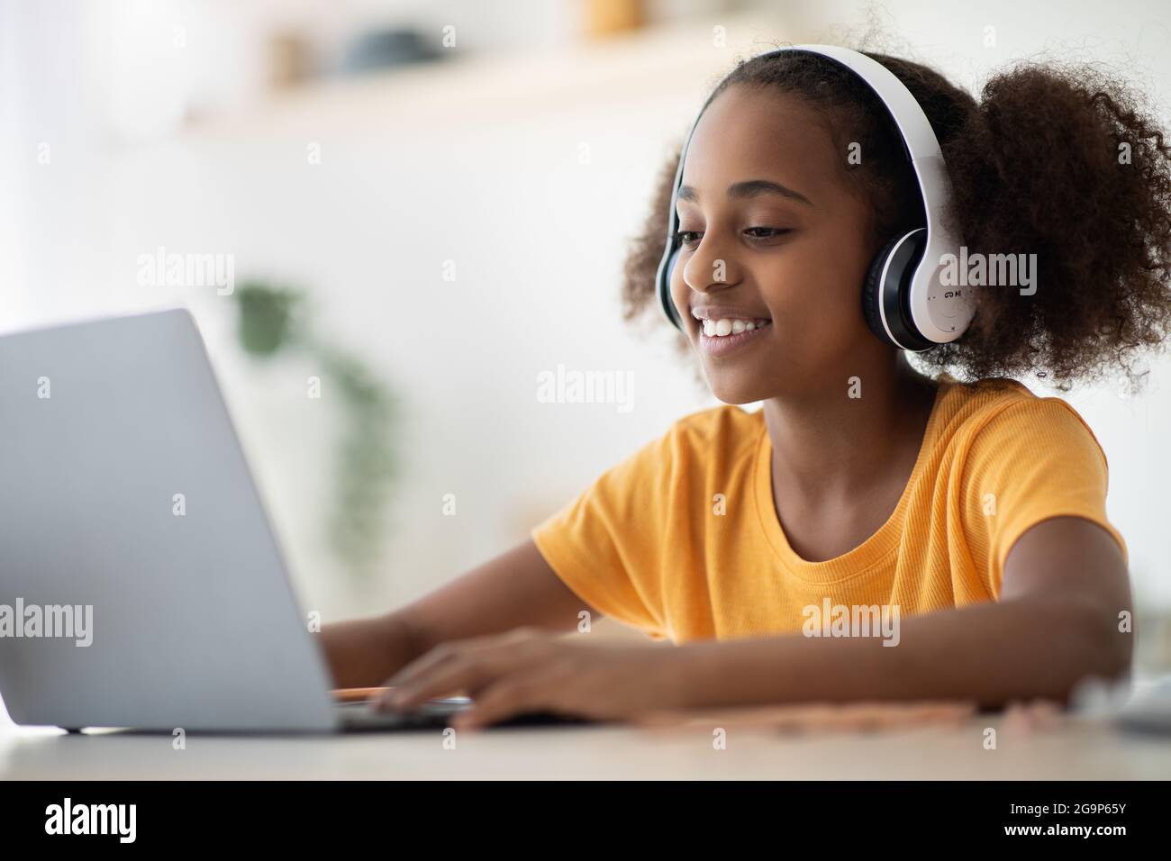 Cheerful black girl studying online, using laptop and headset Stock ...