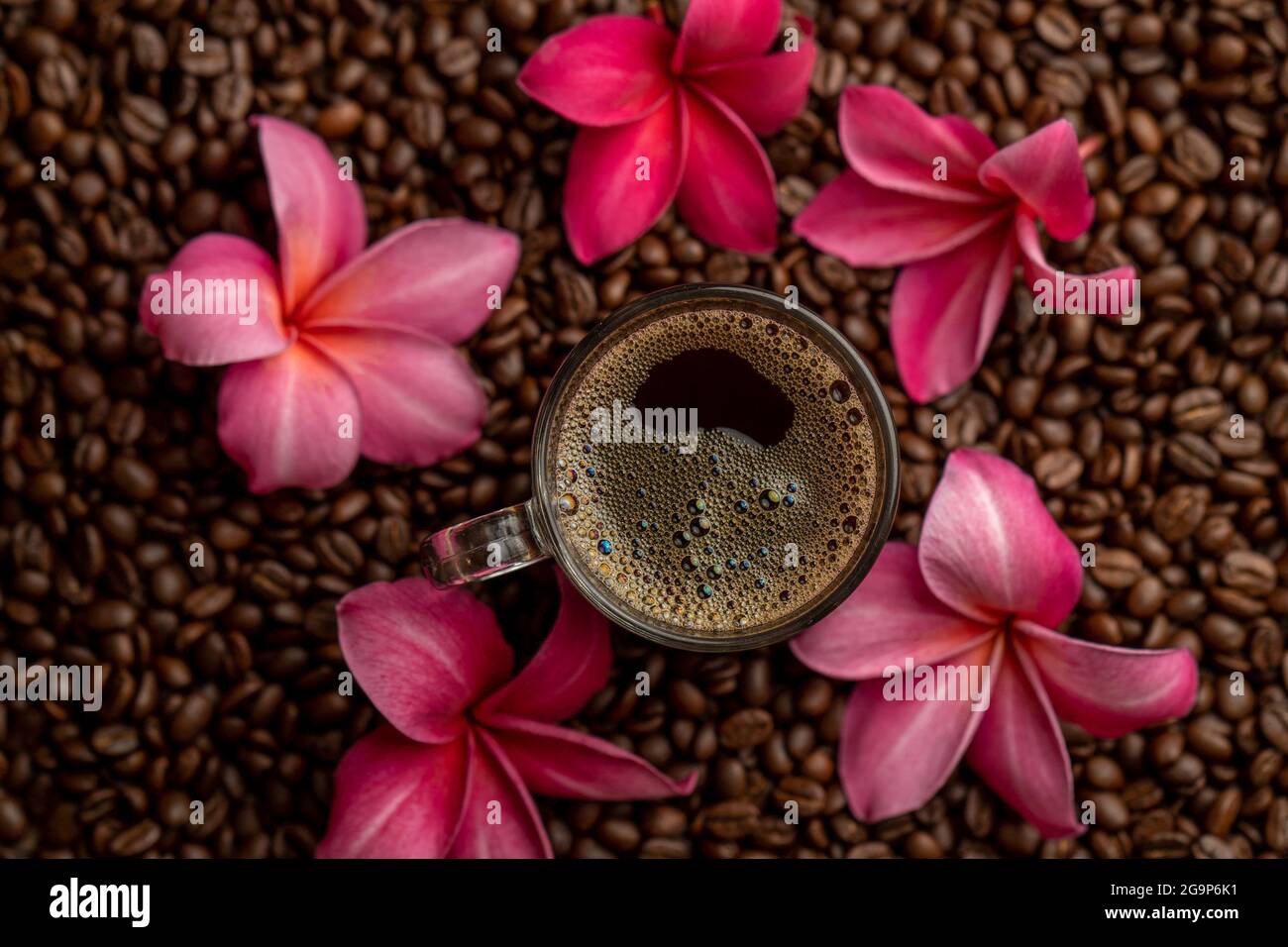 Top view of a cup of coffee on a surface full of coffee beans and pink lily flowers Stock Photo ...