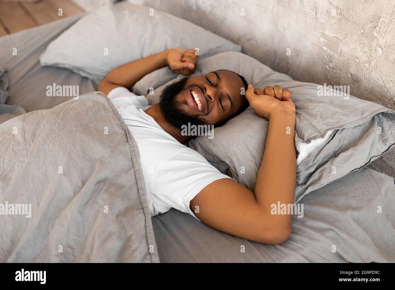 Satisfied young African American man stretching after wake up Stock ...