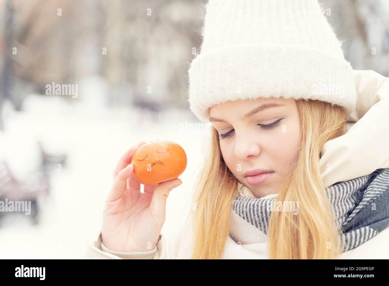 young beautiful woman is sad in winter. holding an orange with a ...