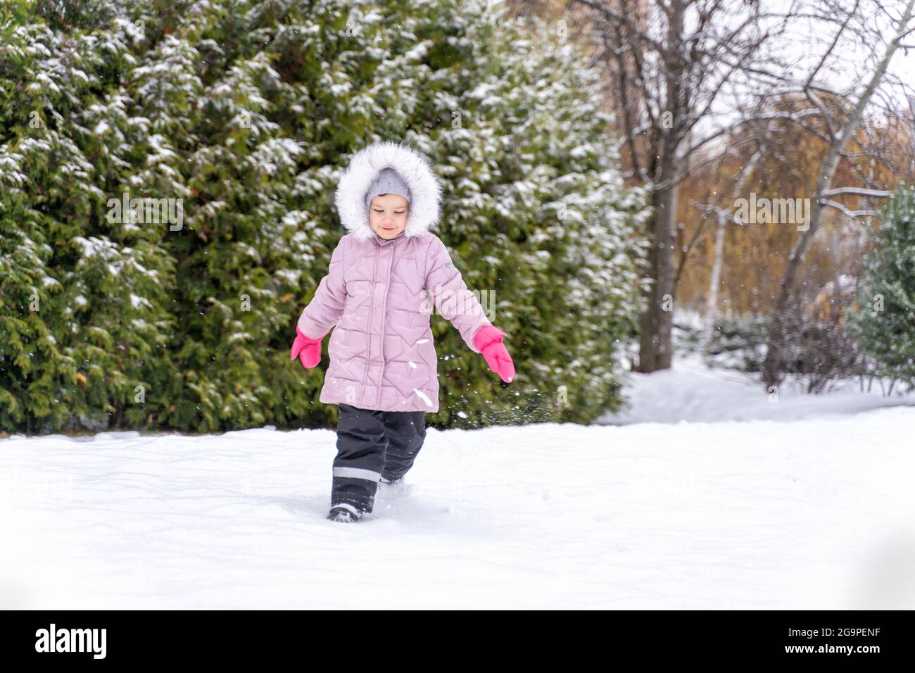 happy little girl girl in pink coat having fun in winter park and ...