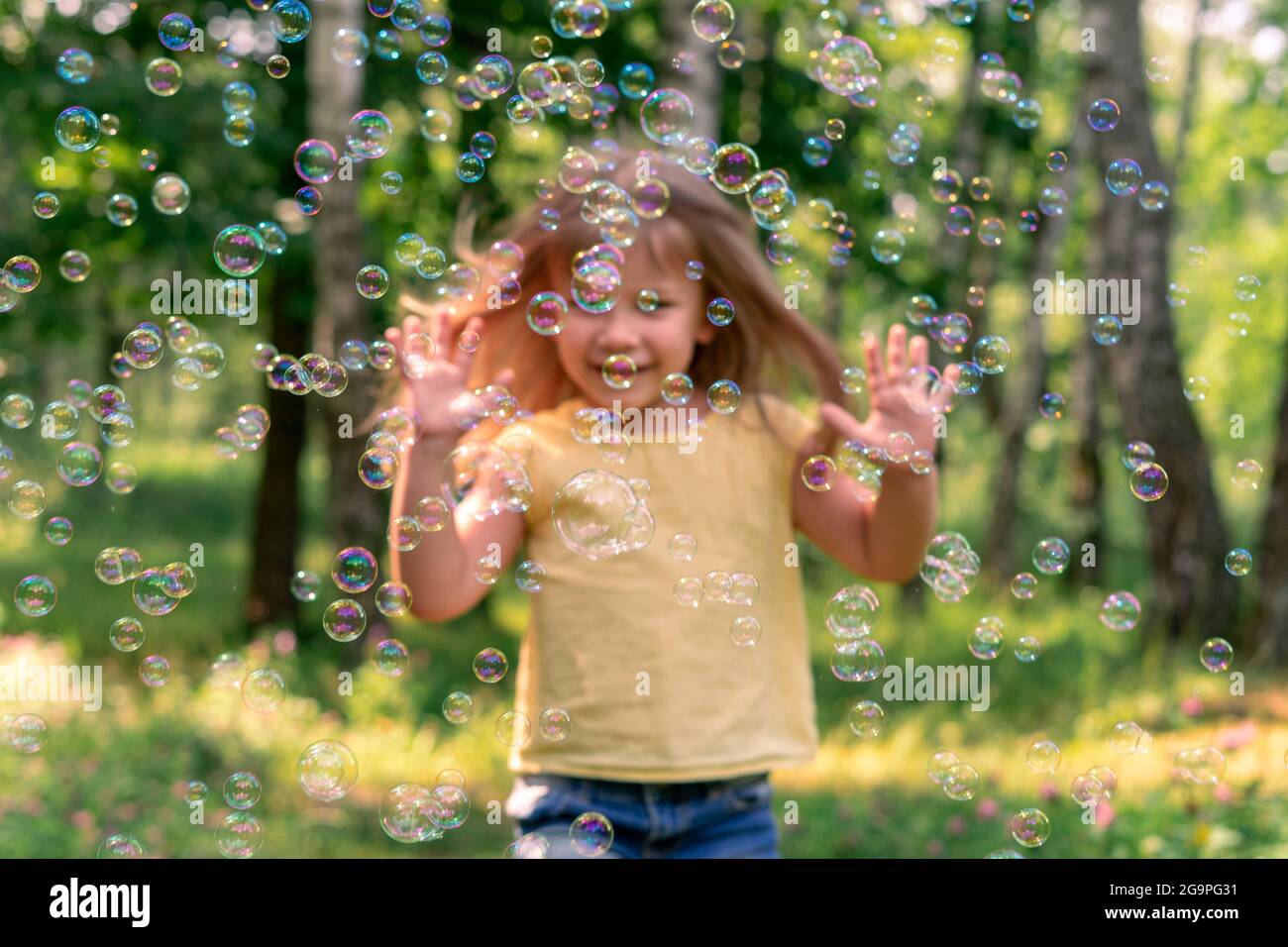 happy caucasian child girl catching a lot of soap bubbles on a summer ...