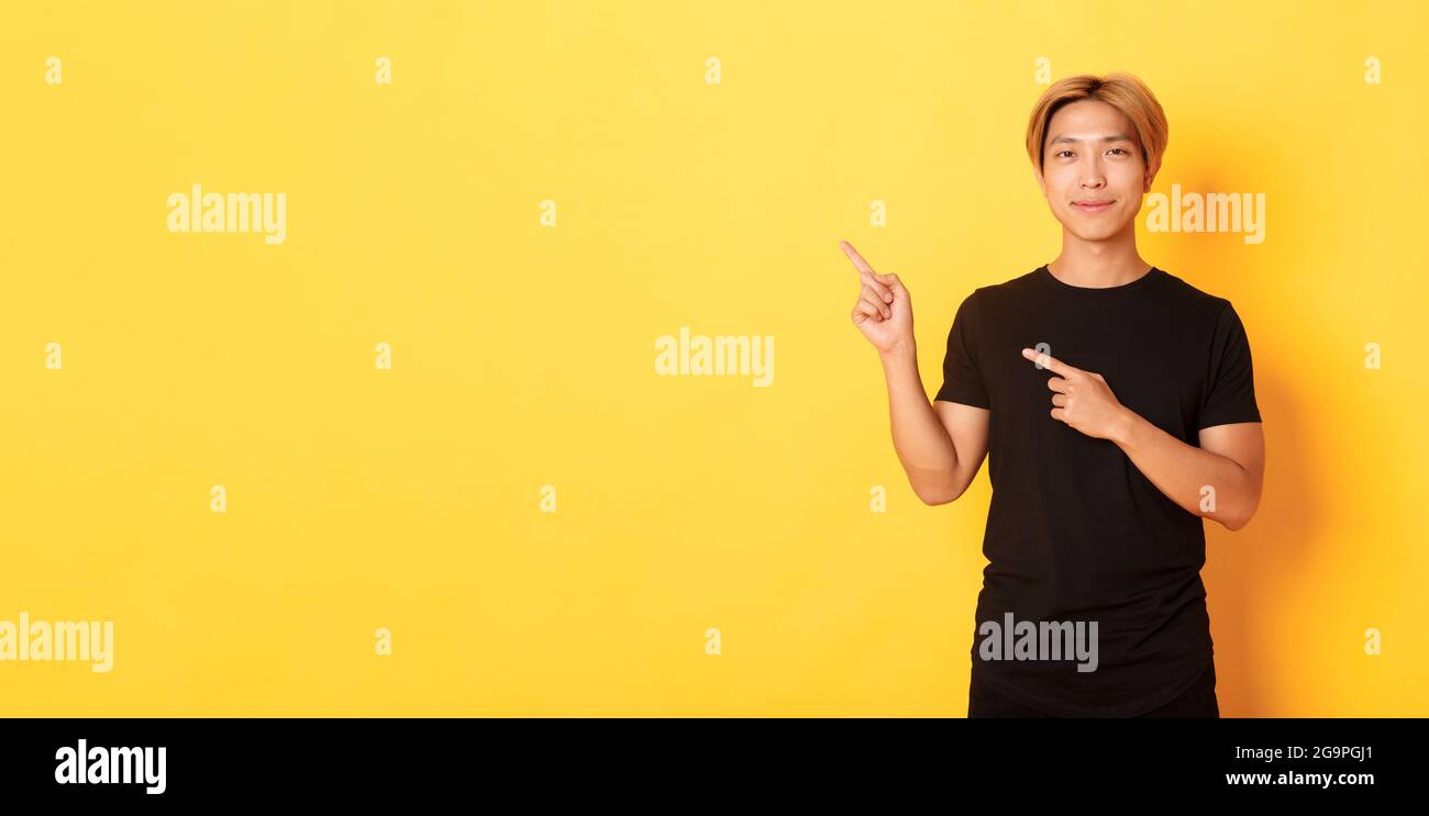 Portrait of smiling handsome asian man in black t-shirt pointing ...