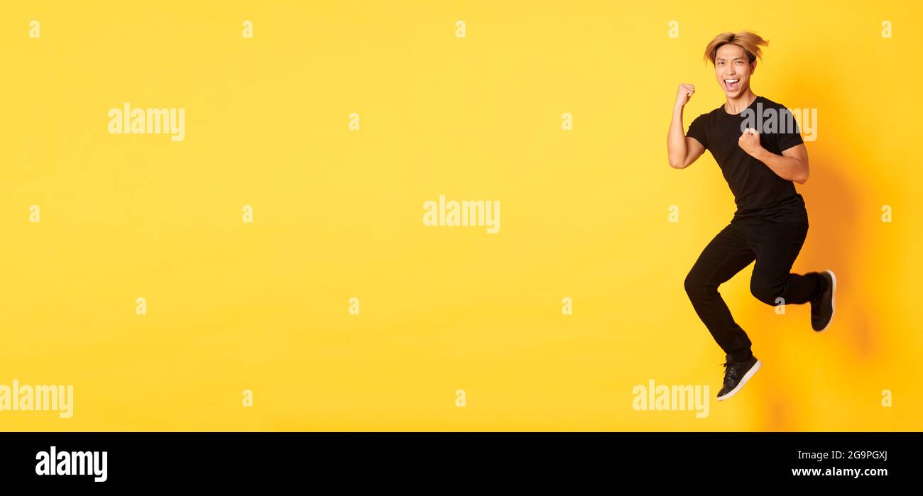 Full-length of happy attractive asian guy in black clothes jumping and ...