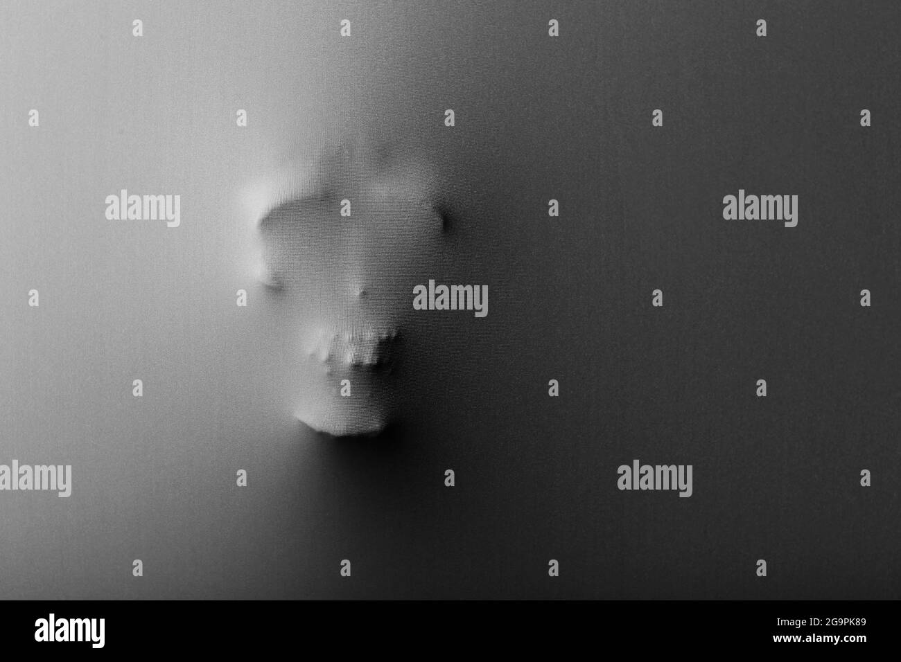 Skull pressing through fabric as horror background Stock Photo - Alamy