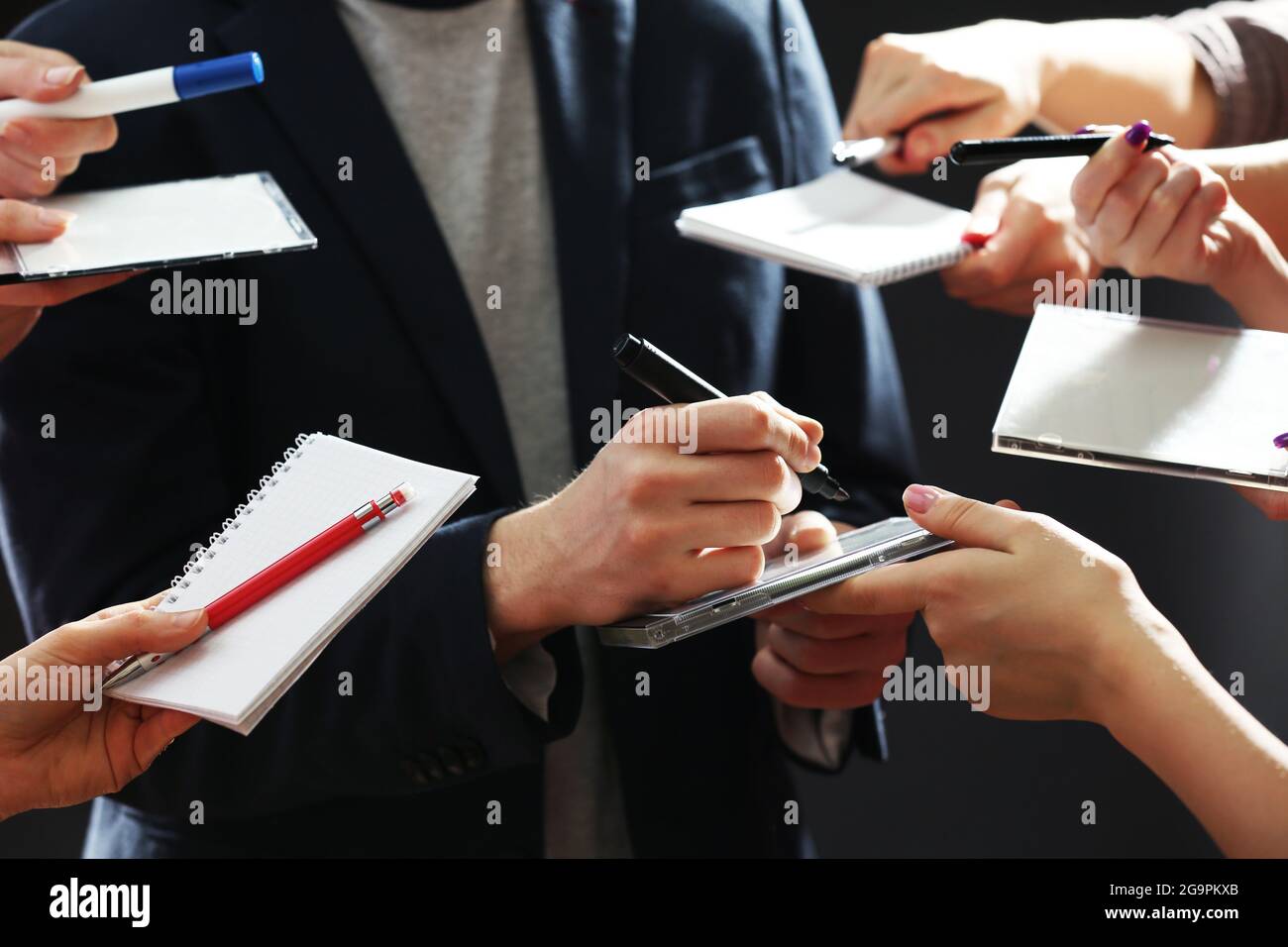 Elegant man signing autograph in notebook on dark background Stock ...
