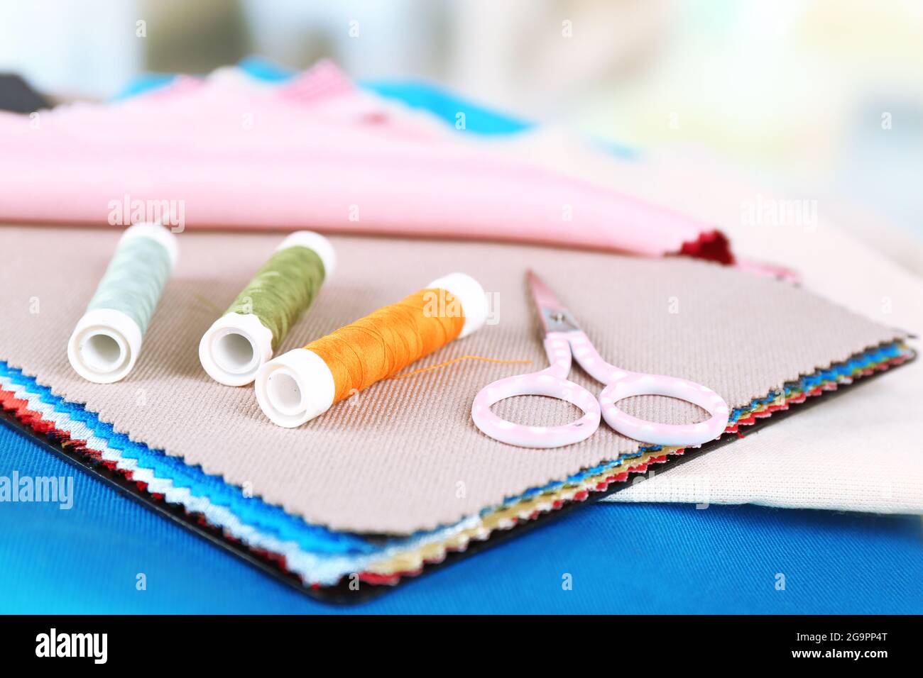 Colorful fabric samples. threads and scissors on table and light ...