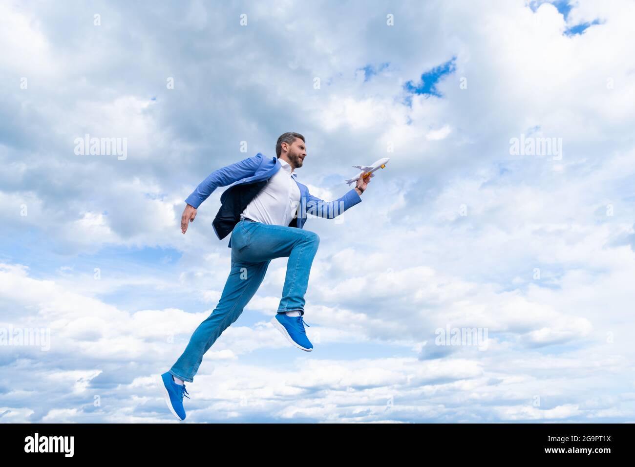happy man businessperson in jacket hold toy plane on sky background run ...