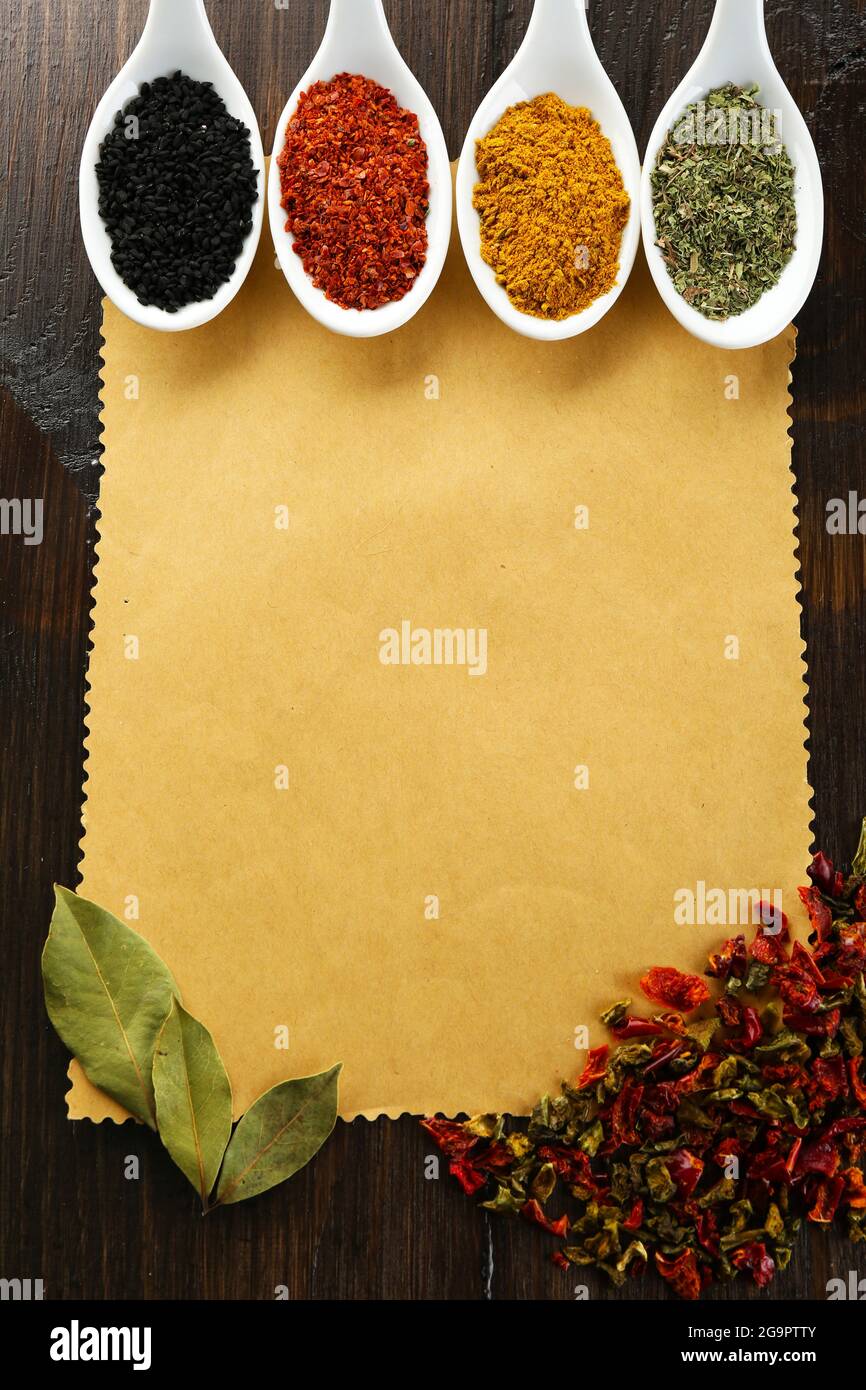 Different kinds of spices in ceramics spoons on blank paper sheet on ...