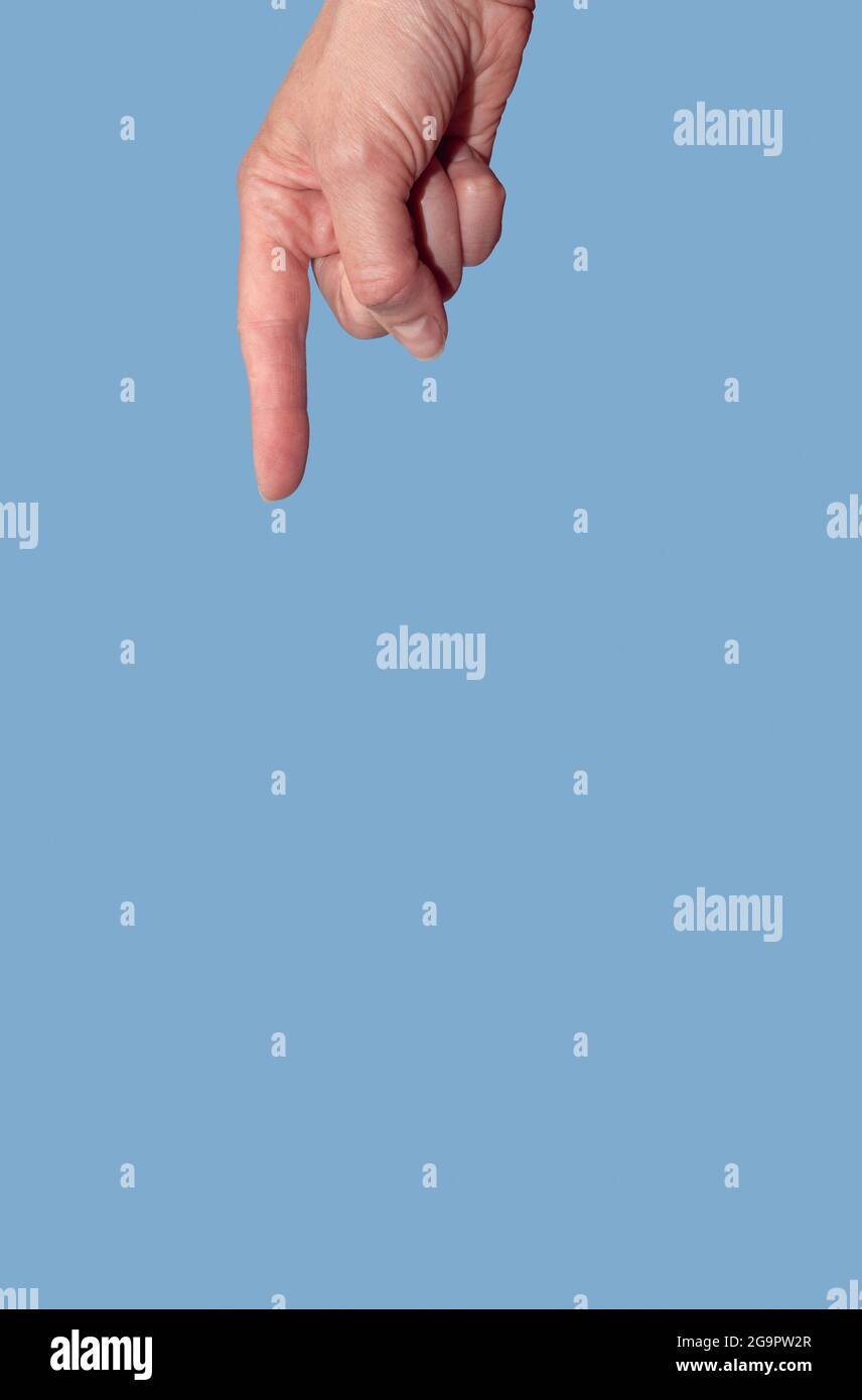 Female hand pointing from top to bottom isolated on blue background ...