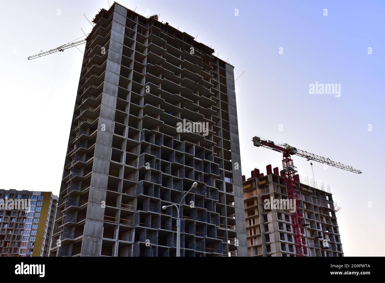 Tower cranes in action at construction site on blue sky background. A ...