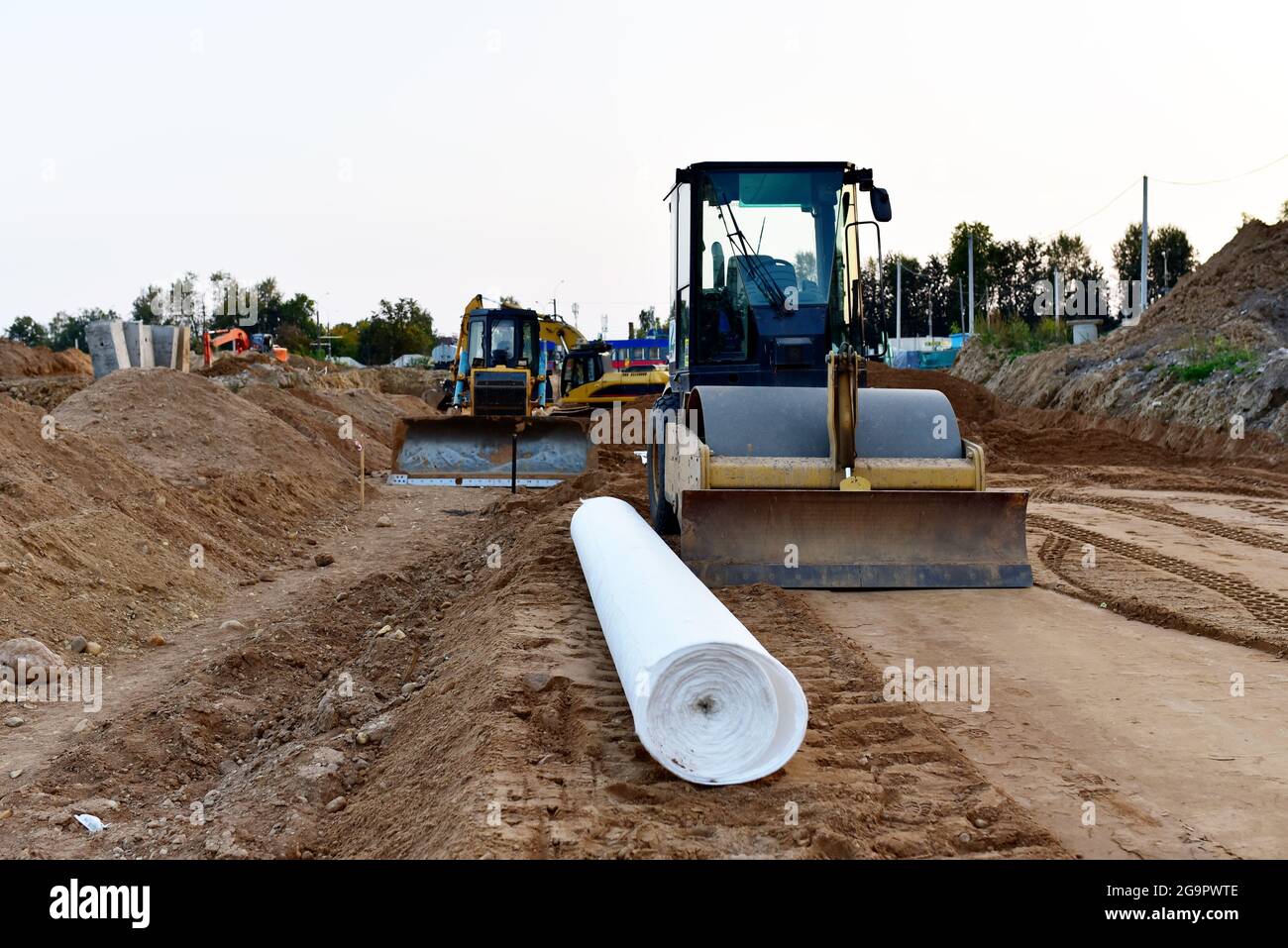 Road construction using road machinery. Soil compactor and dozer at ...