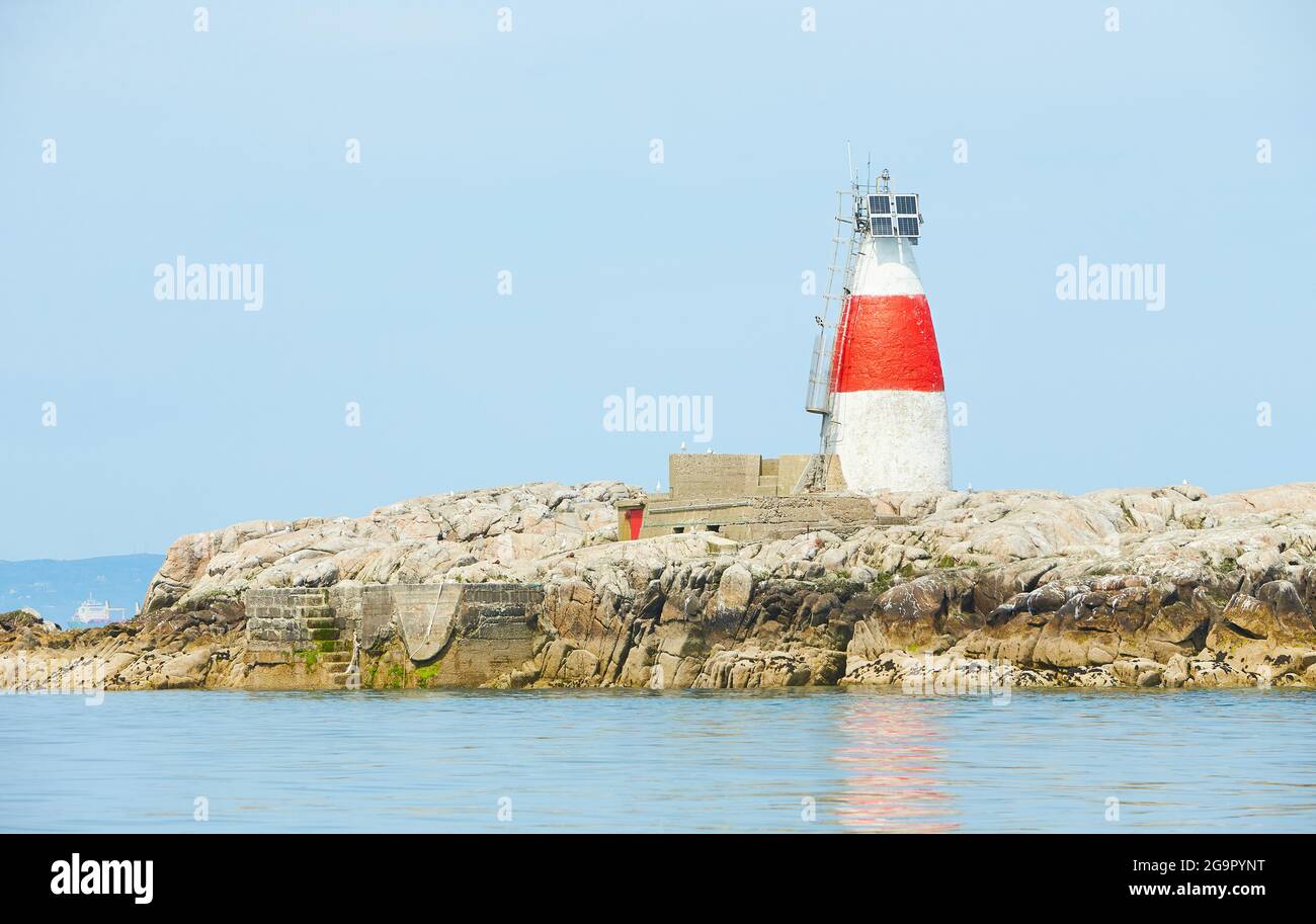 Old Muglins Lighthouse on the isolated island the backdrop of the blue ...