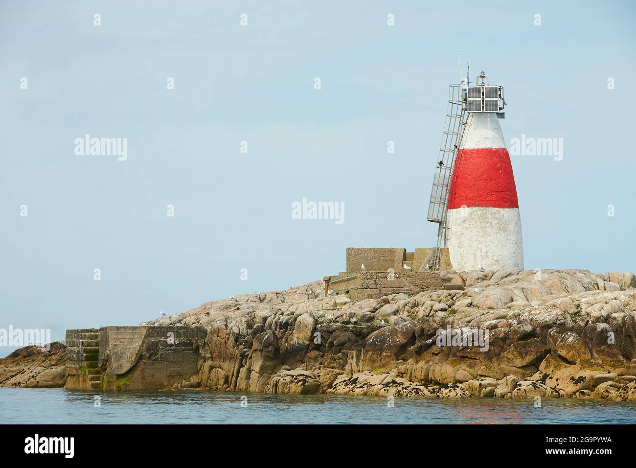 Old Muglins Lighthouse on the isolated island the backdrop of the blue ...