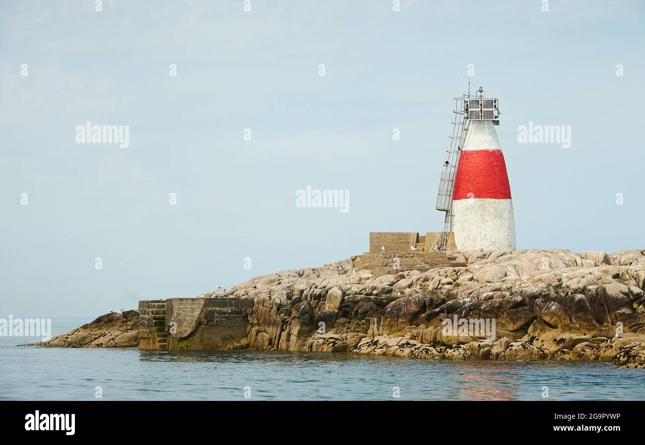 Old Muglins Lighthouse on the isolated island the backdrop of the blue ...