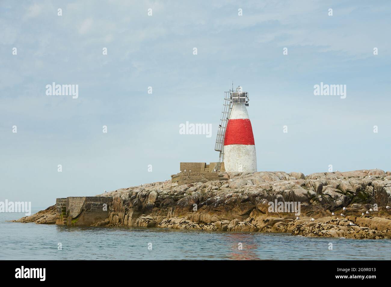 Old Muglins Lighthouse on the isolated island the backdrop of the blue ...