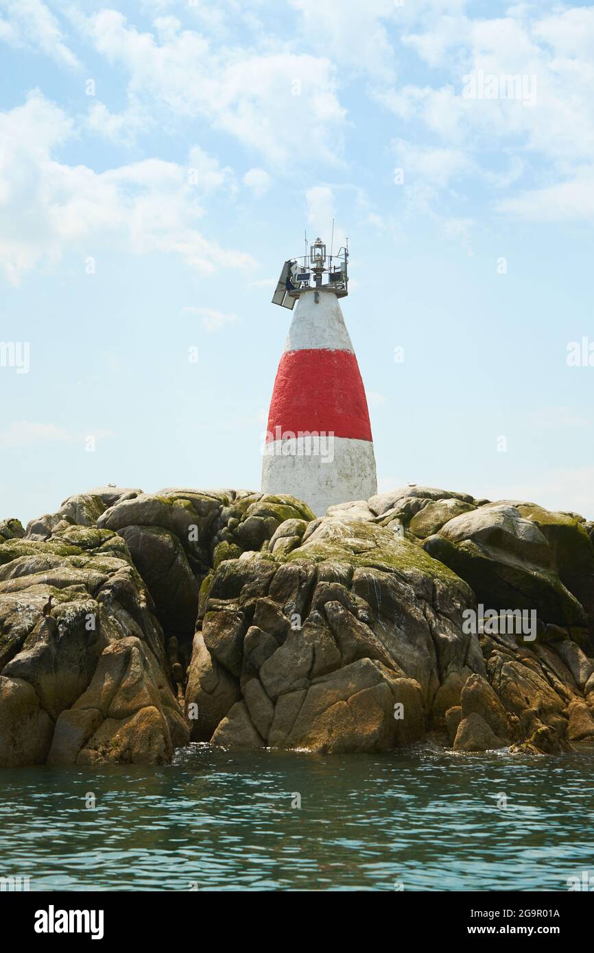 Old Muglins Lighthouse on the isolated island the backdrop of the blue ...