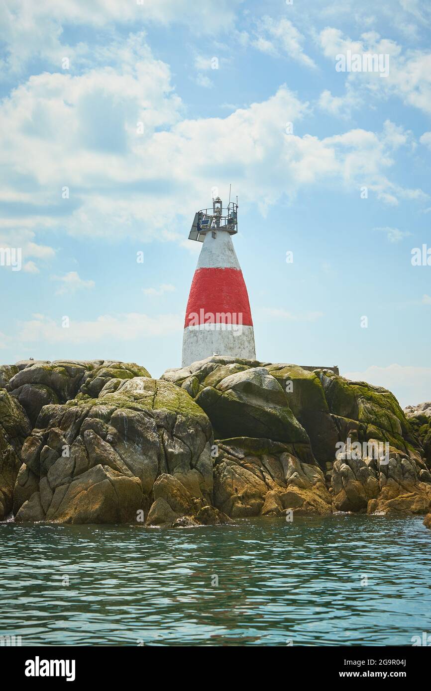 Old Muglins Lighthouse on the isolated island the backdrop of the blue ...