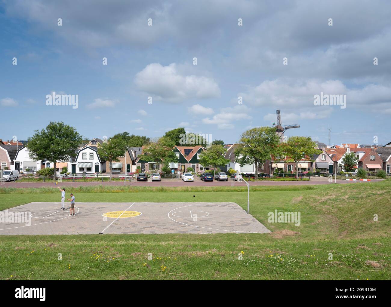 people play basketball in dutch village with windmill of oudeschild on ...