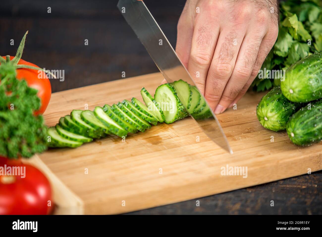 Close up on male hands cutting cucumber, making salad. Chief cutting ...