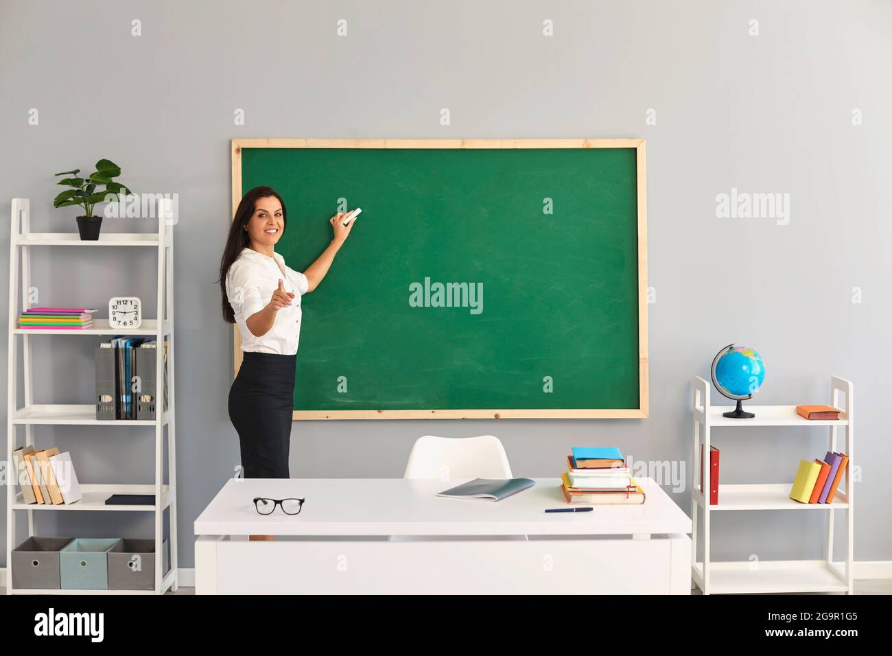 The teacher teach writes a lesson on the blackboard at school Stock ...