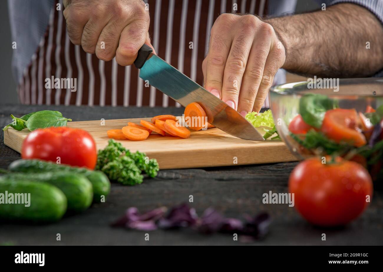 Close up on male hands cutting carrot, making salad. Chief cutting ...