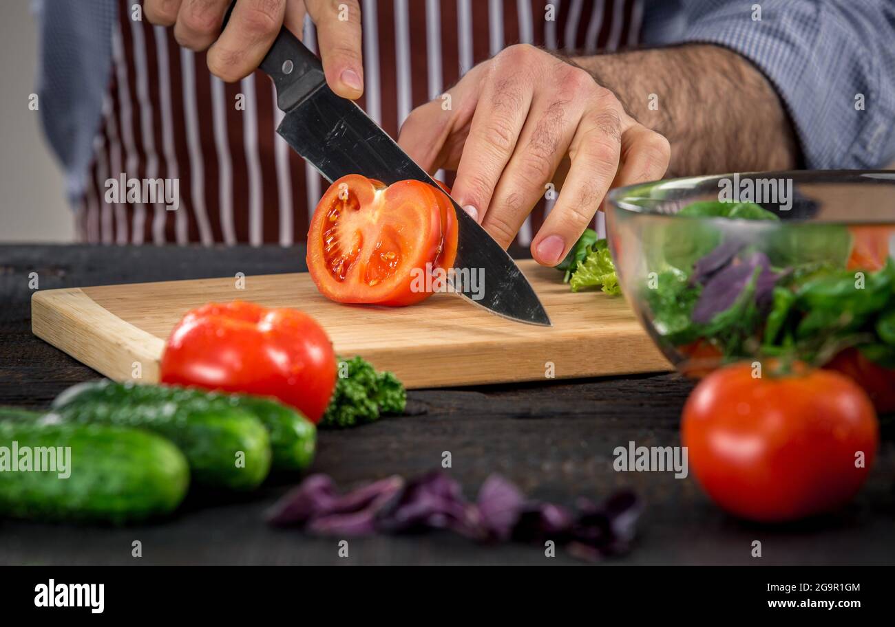 Close up on male hands cutting tomato, making salad. Chief cutting ...