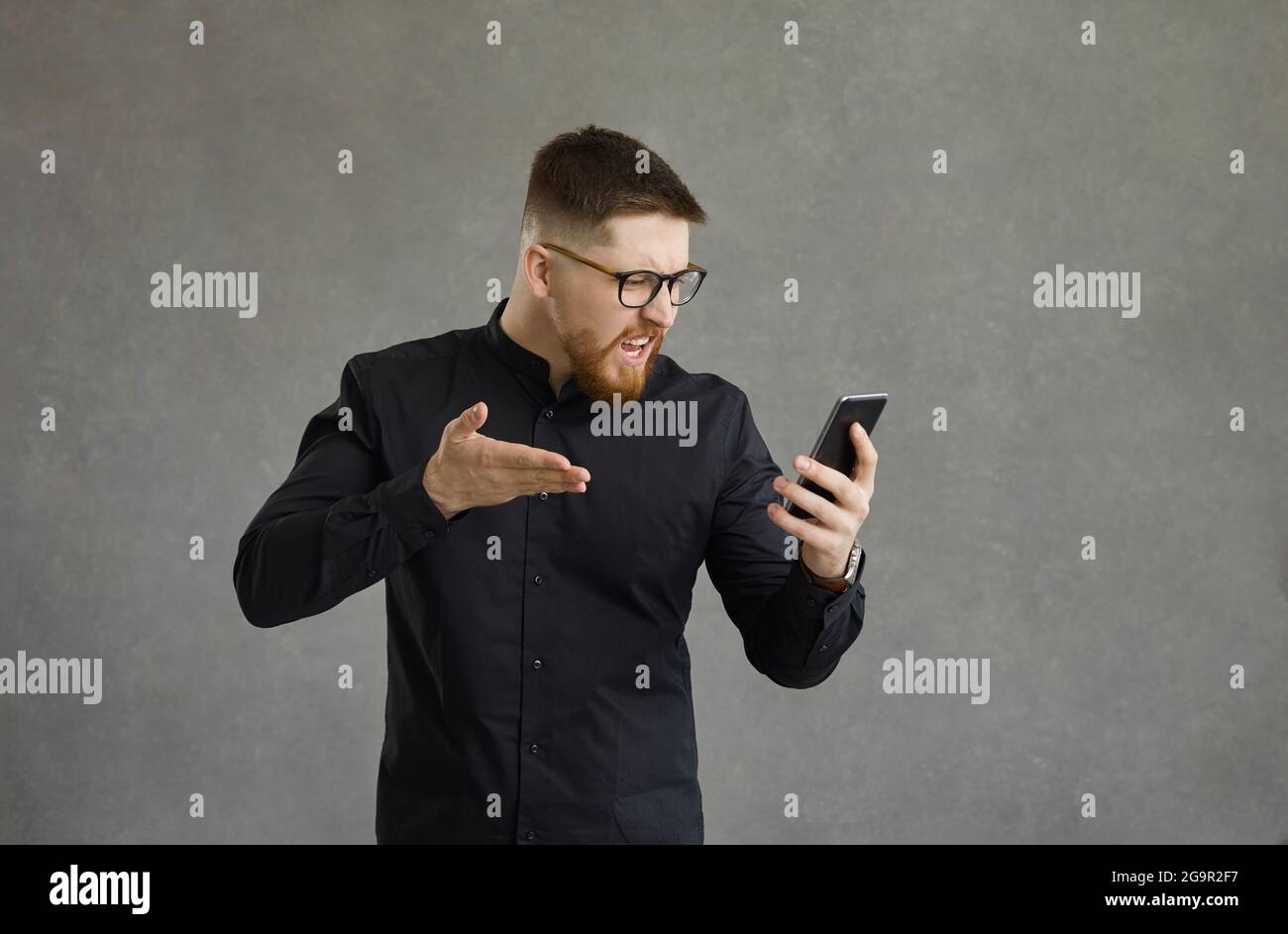 Angry man waves his hand and indignantly shouts at his smartphone after ...