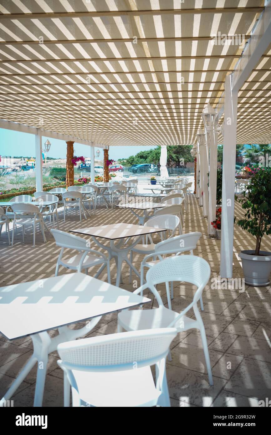 tables and chairs in a cafe under a canopy Stock Photo - Alamy