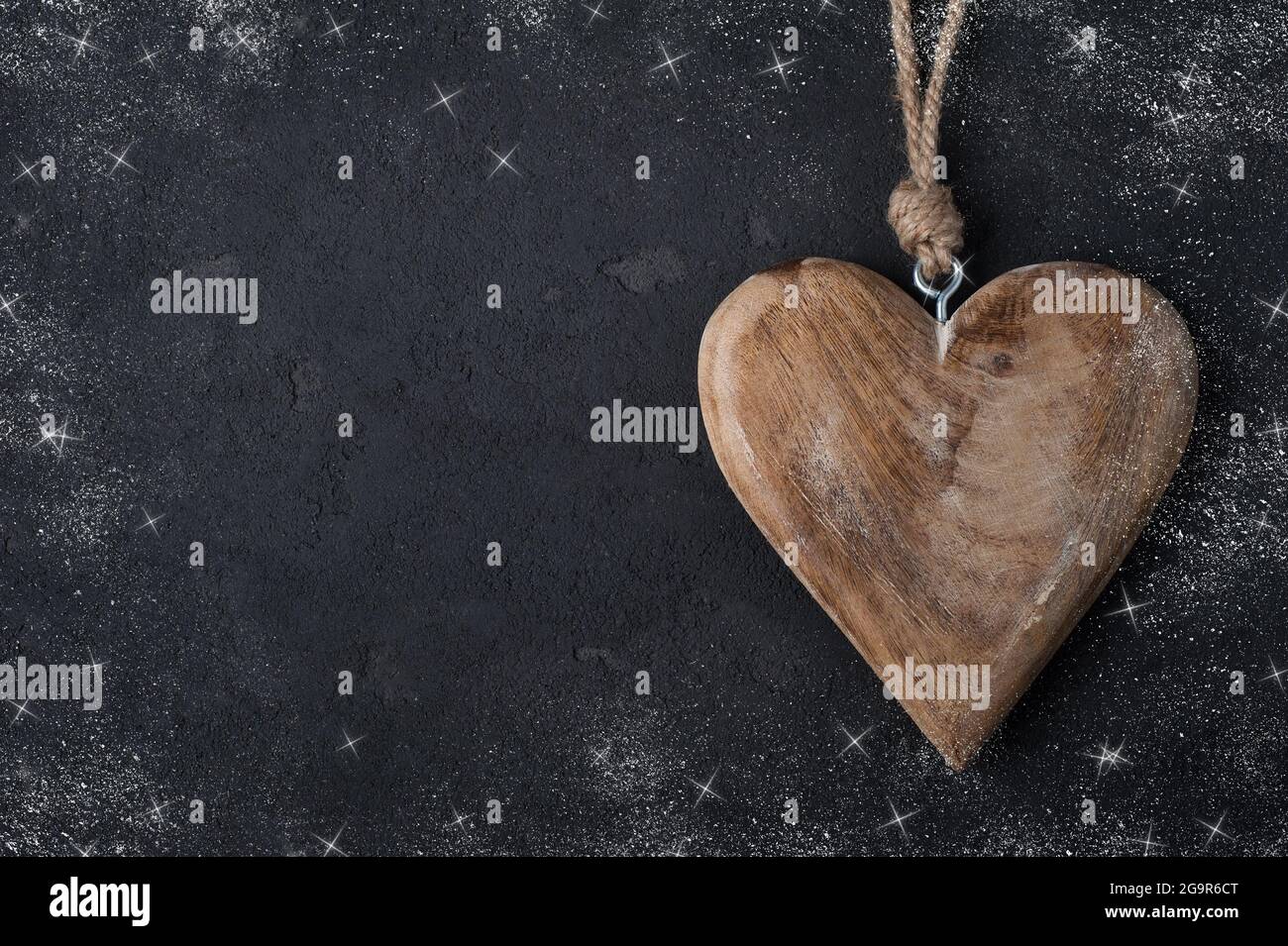Black concrete background with wooden heart, place for chalk text. Snow ...